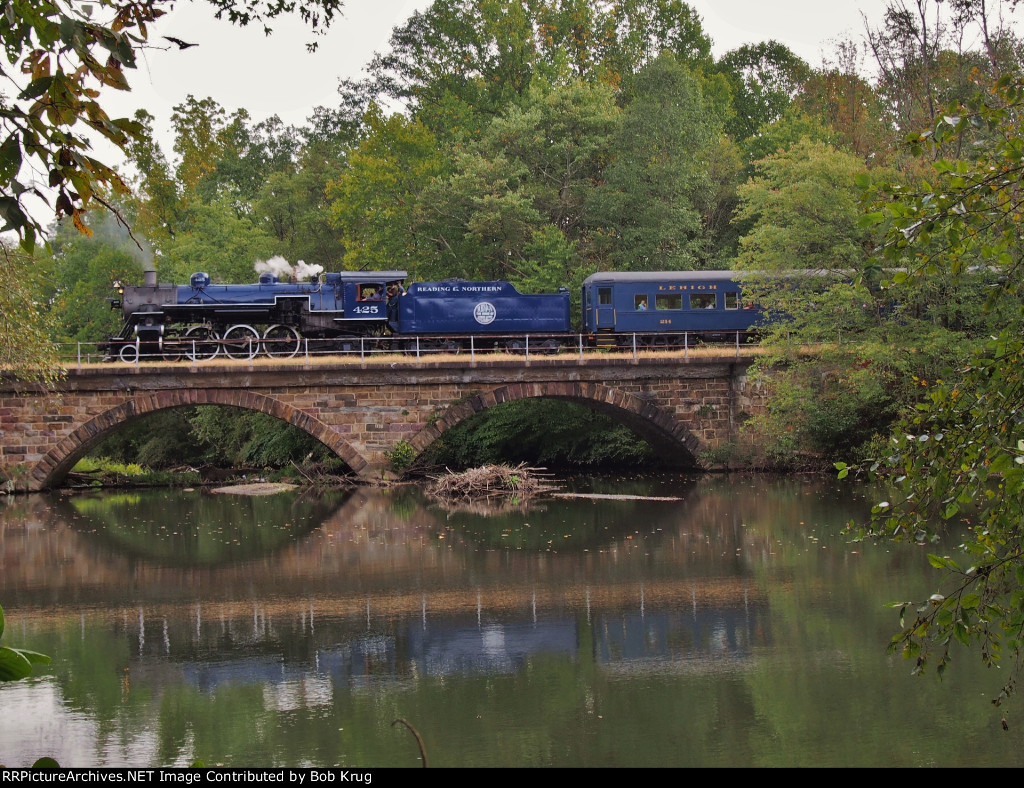RBMN 425 backs the 11 a.m. train eastbound over the ex-Reading Company stone arch bridge at ...